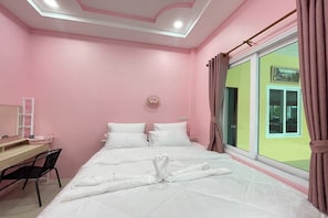 Quarto com cama, escrivaninha, cadeira, janela com cortinas e luminária na parede.