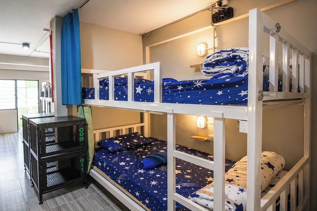 Quarto com beliche, colcha estampada com estrelas, escrivaninha com computador e estante.