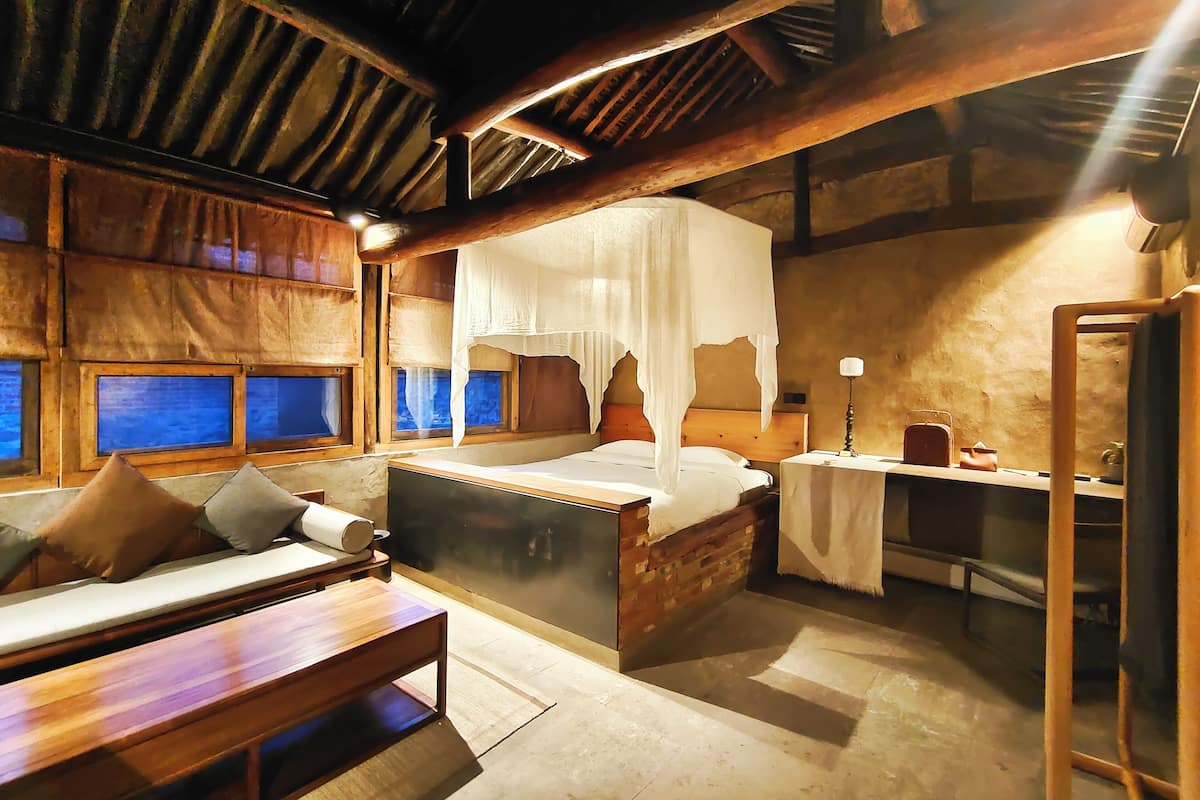 Um quarto com uma cama, um banco, uma mesa e uma escrivaninha.