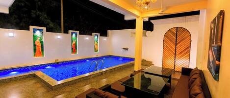 Piscina com fundo de vidro, mesa de vidro e um sofá.