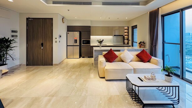 Uma sala de estar moderna com um sofá, uma mesa de centro e vista para a cidade.
