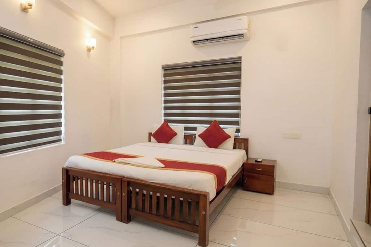 Quarto de hotel com cama, duas mesas de cabeceira, ar condicionado e janela com persianas.