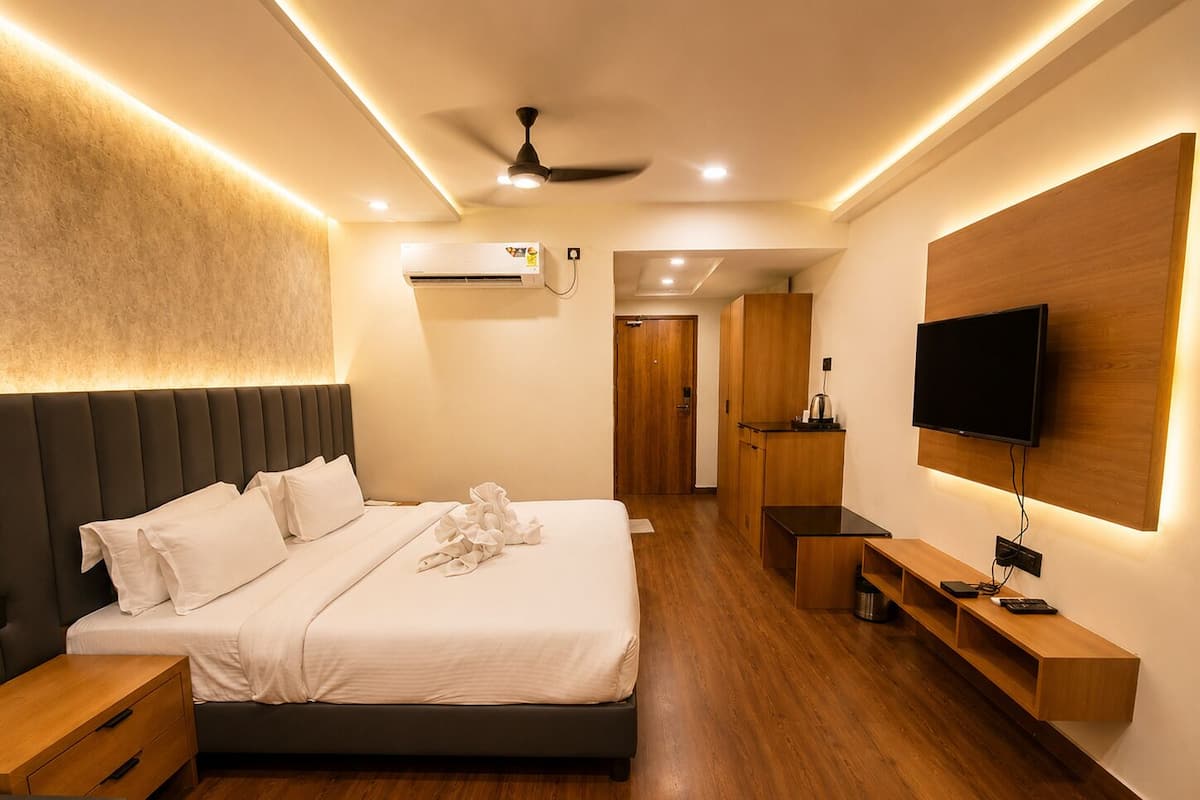 Um quarto moderno com cama, mesas de cabeceira, televisão e ventilador de teto.