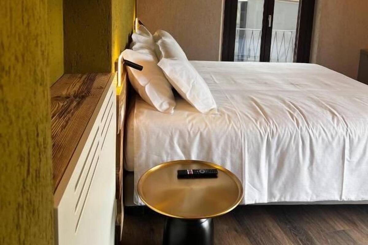 Um quarto com cama, mesa de cabeceira, janela com vista e porta.