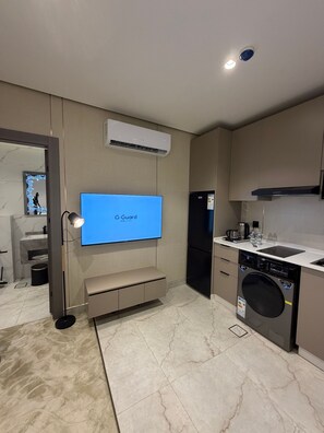 Uma cozinha moderna com máquina de lavar embutida, TV de tela plana e cafeteira.