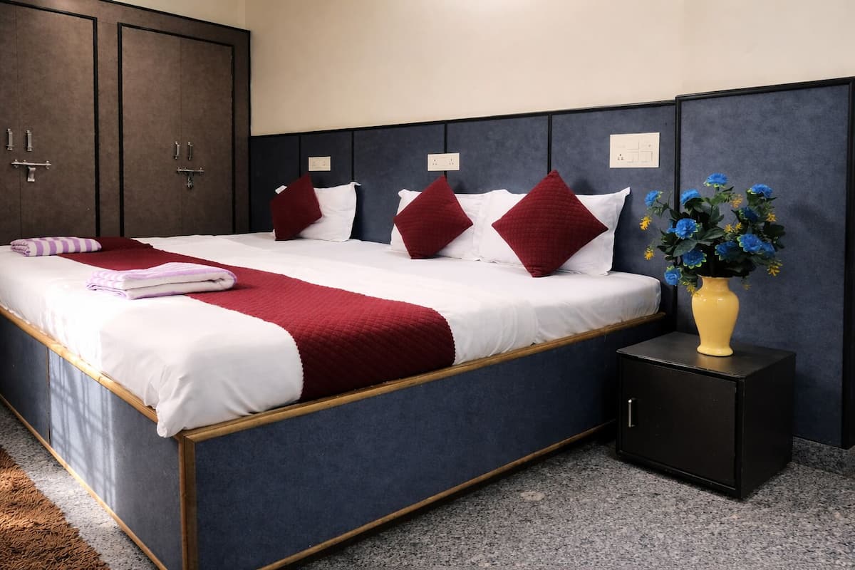 Quarto de hotel com uma cama, mesa de cabeceira, um vaso com flores e um guarda-roupa.