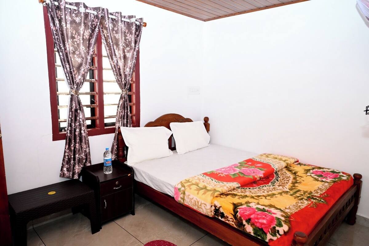 Quarto com cama, mesa de cabeceira, cabeceira de madeira, janela com cortinas e luminária na parede.