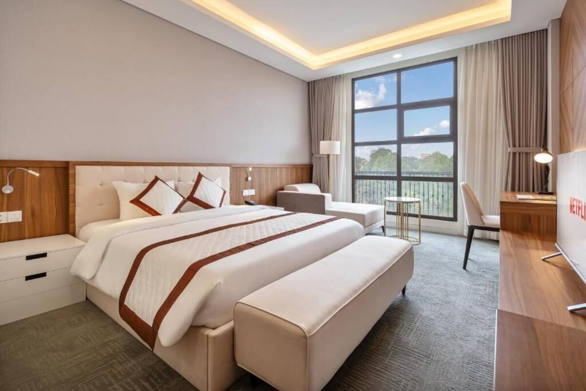Quarto de hotel com uma cama grande, uma escrivaninha, uma cadeira e uma televisão.