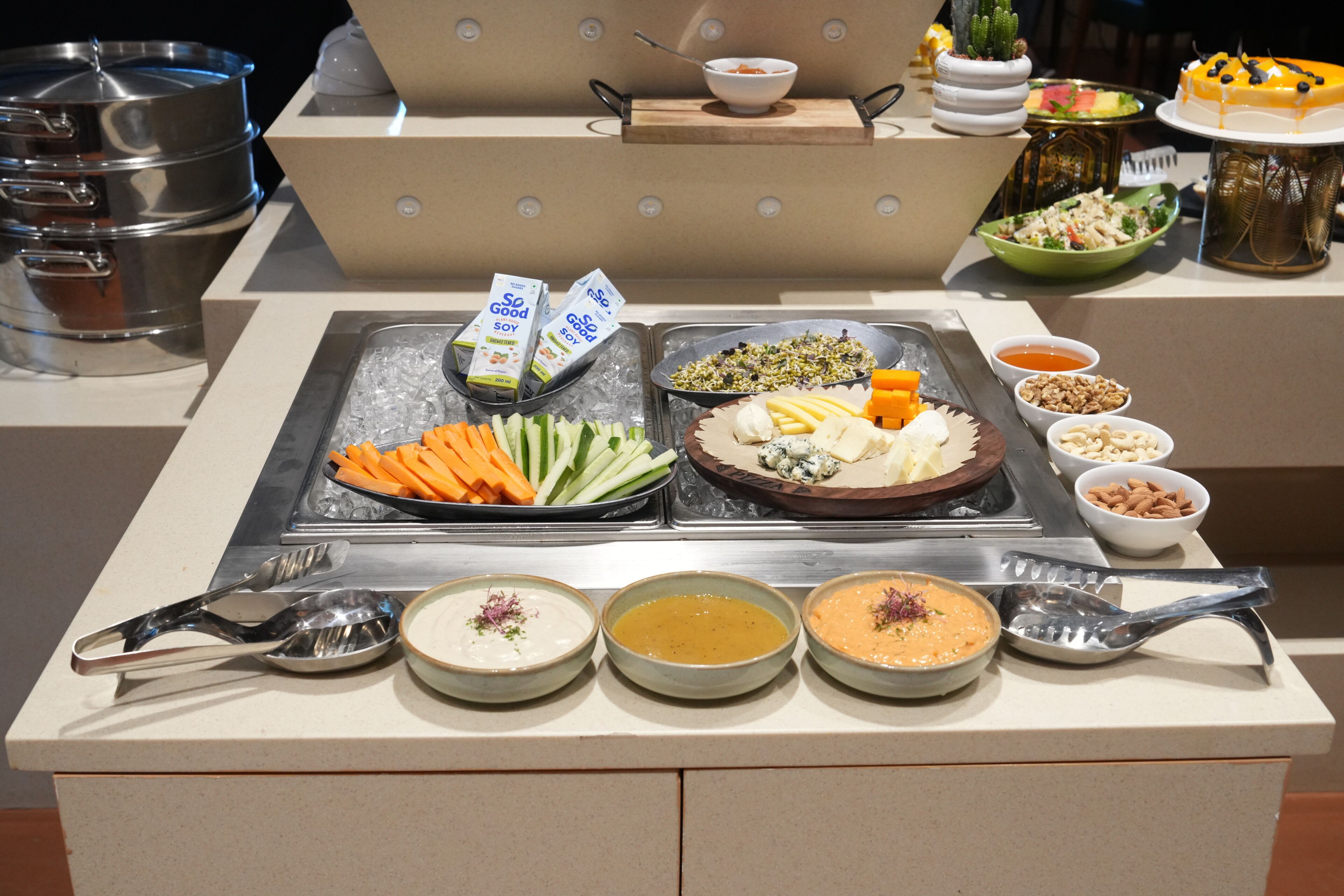 Mesa de buffet com diversos alimentos, utensílios e recipientes.