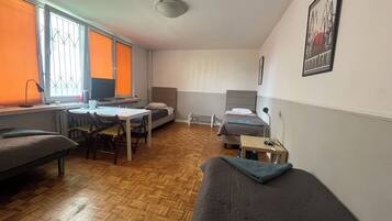 Quarto pequeno com cama, escrivaninha e cadeira.