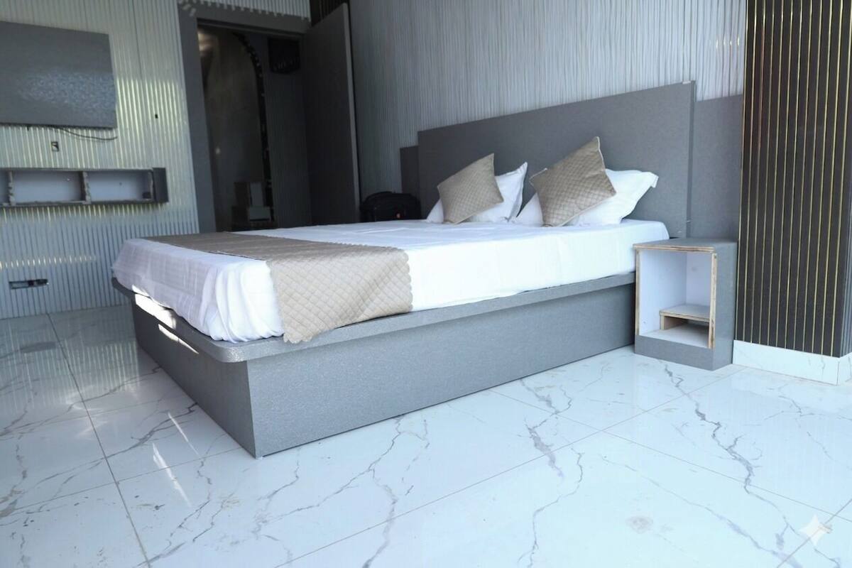 Quarto moderno com uma cama grande, uma mesa de cabeceira e um nicho embutido.