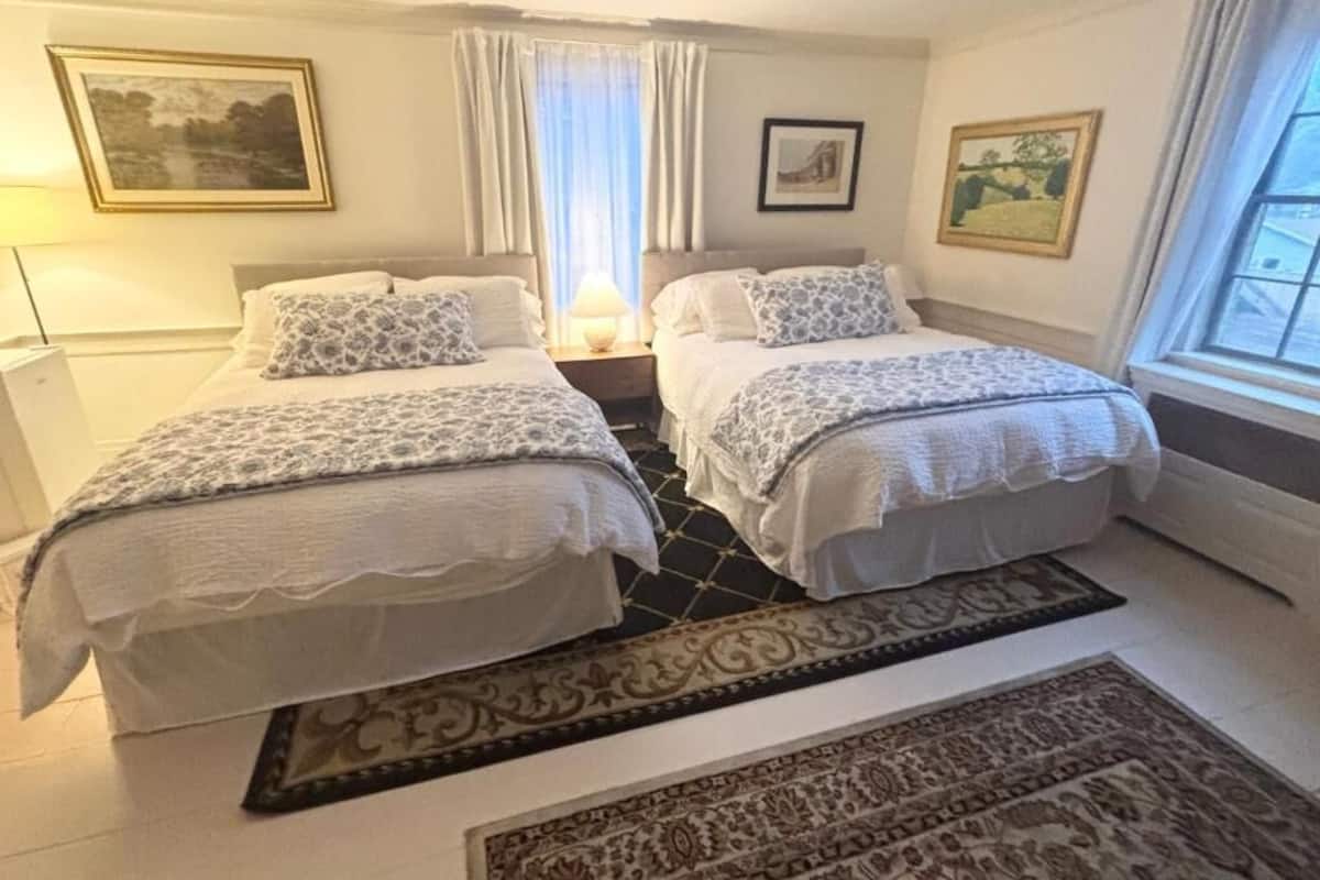 Quarto de hotel com duas camas, uma janela grande e vista para o exterior.