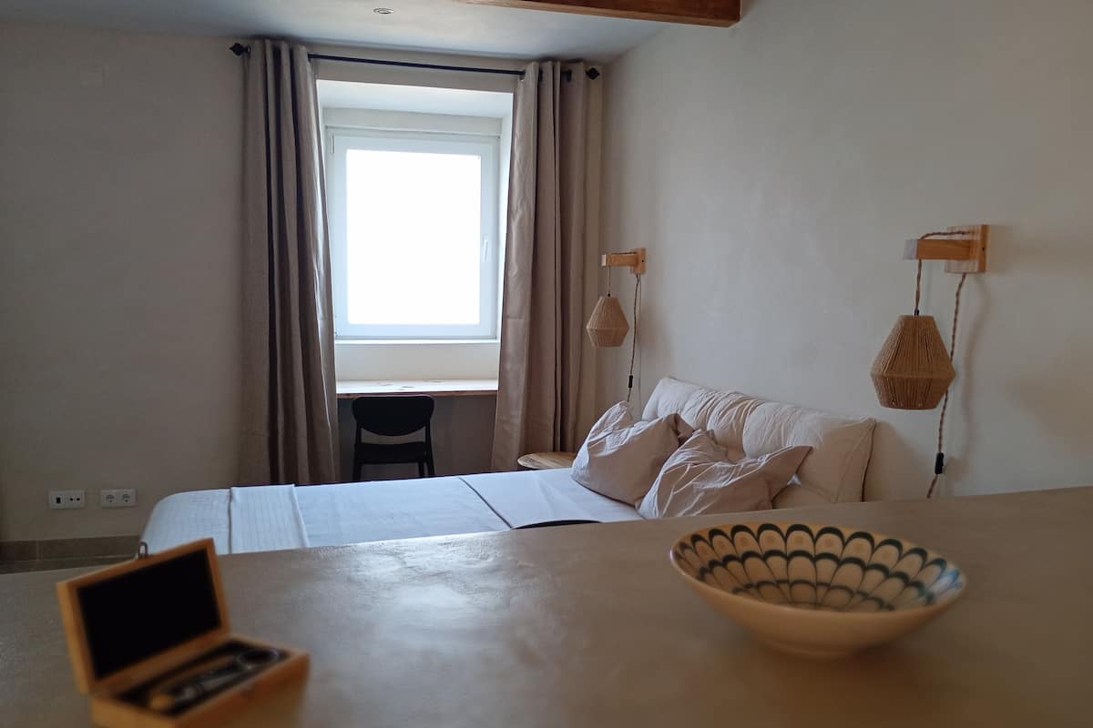 Quarto com cama, escrivaninha, cadeira, tigela e luminária pendente.