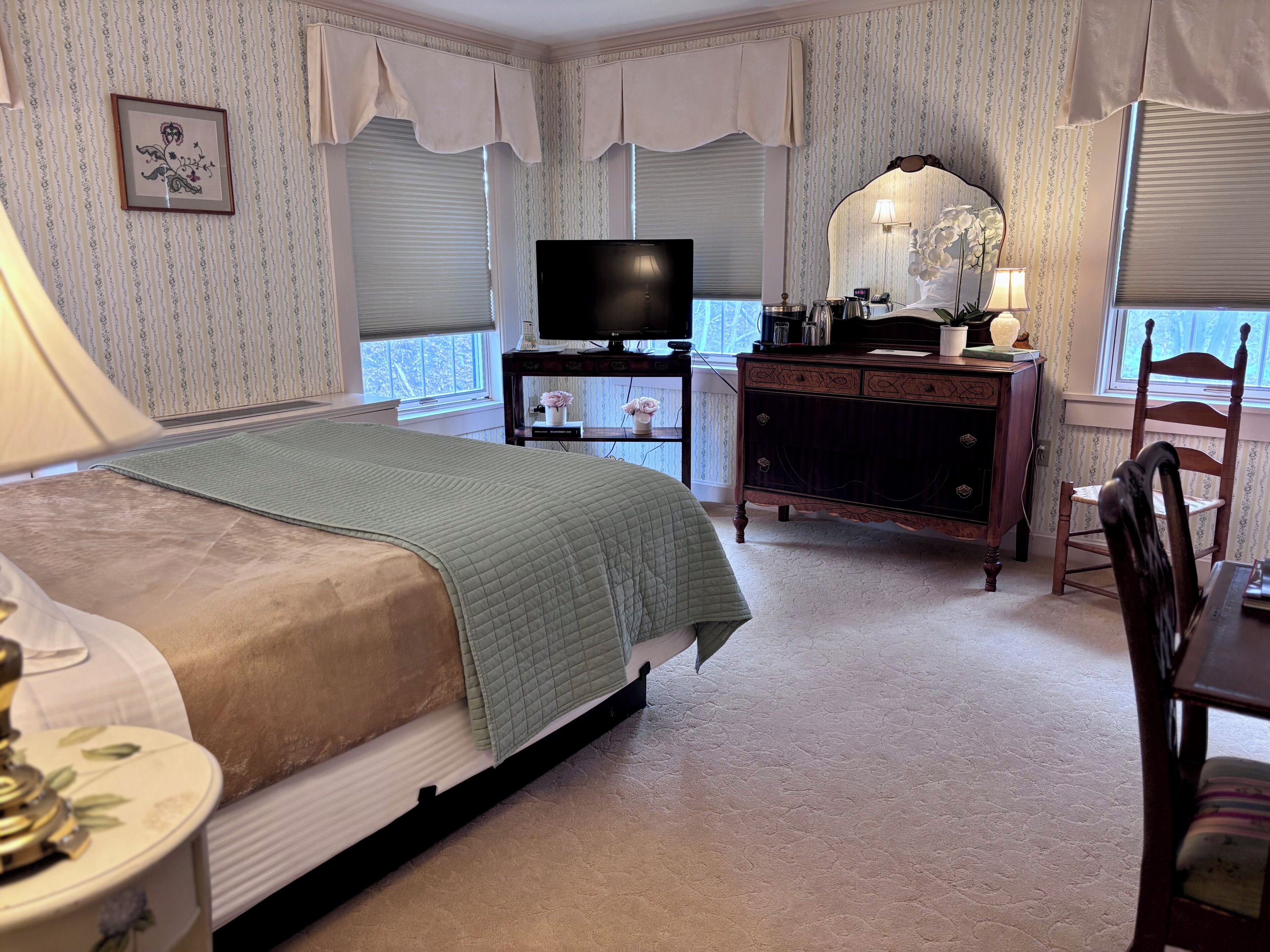 Quarto com cama, cômoda, televisão e uma cadeira.