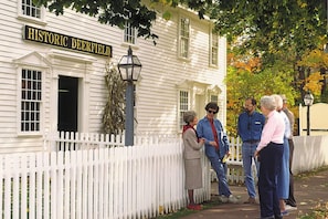 Um edifício histórico com cerca branca e uma placa com a inscrição 'Historic Deerfield'.