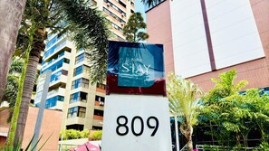 Placa de hotel com o número 809 e vista parcial de um edifício com vários andares e varandas.