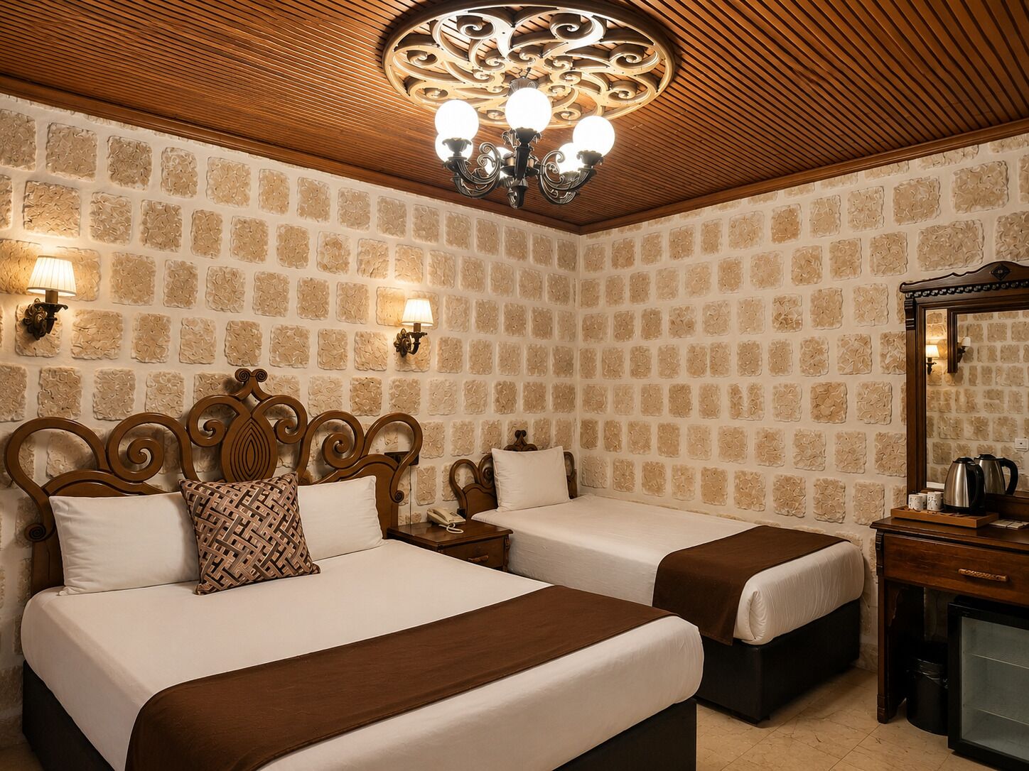 Quarto de hotel com duas camas, teto de madeira, azulejos decorativos na parede, um candelabro e um espelho.