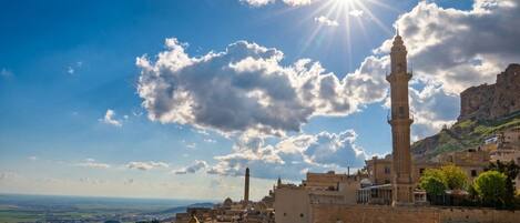 Uma cidade histórica com um minarete imponente, edifícios em terraços e uma vista clara da paisagem circundante.