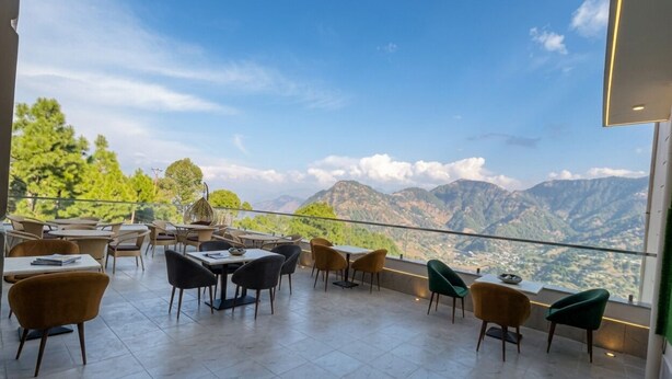 Terraço com mesas e cadeiras, com vista para uma paisagem montanhosa.