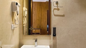 Casa de banho com lavatório branco, toucador de madeira, secador de cabelo, espelho e um porta-toalhas.