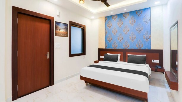 Quarto com cama, ventoinha no teto, televisão na parede e papel de parede estampado.