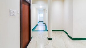 Um corredor com porta de madeira, câmera de segurança e interruptor de luz na parede.