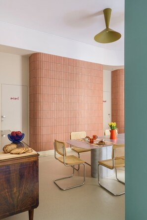Uma área de refeições com uma mesa, cadeiras, um vaso decorativo e uma parede com padrão quadriculado.