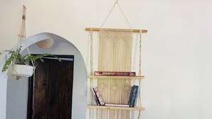 Uma tapeçaria de macramé com prateleiras, uma planta pendente e uma porta.