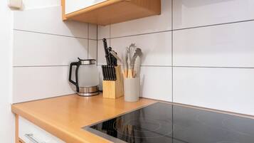 Cozinha com fogão por indução preto, relógio digital e máquina de café.