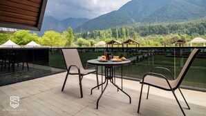Um terraço com mesa e cadeiras, com vista para uma paisagem montanhosa.