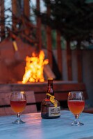 Uma garrafa de Grand Marnier e dois copos sobre uma mesa, com uma lareira ao fundo.