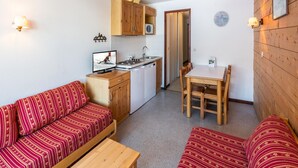 Quarto compacto com cozinha compacta, espaço de refeições e sofá.