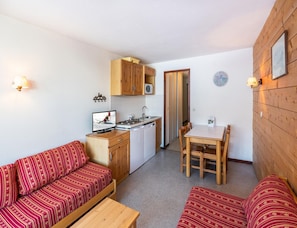 Quarto compacto com cozinha compacta, espaço de refeições e sofá.