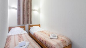 Quarto de hotel com duas camas de solteiro, um espelho e um aparelho de luz sobre o espelho.