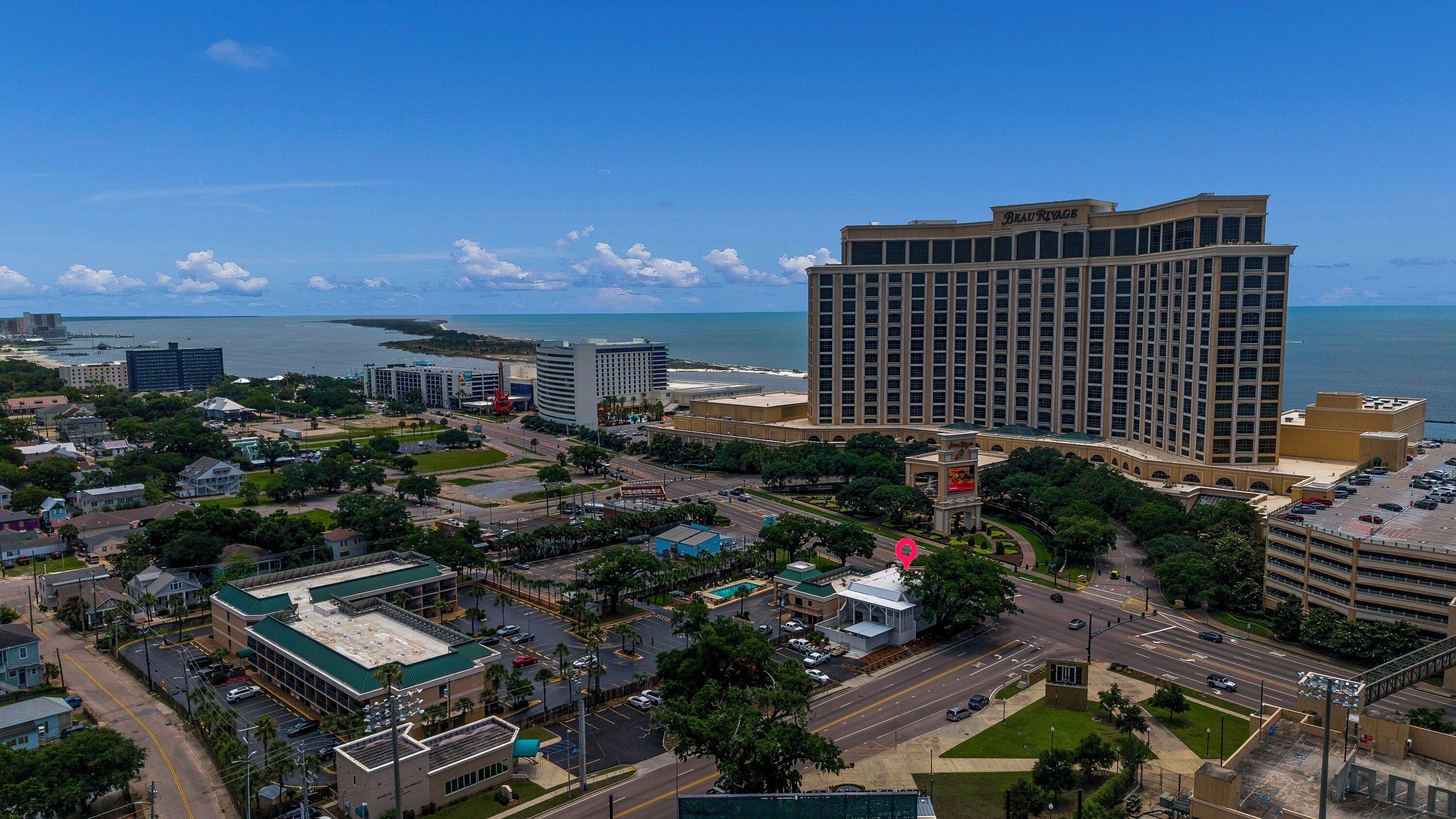 Um hotel alto com vista para o oceano, cercado por um cenário urbano com diversos edifícios e ruas.
