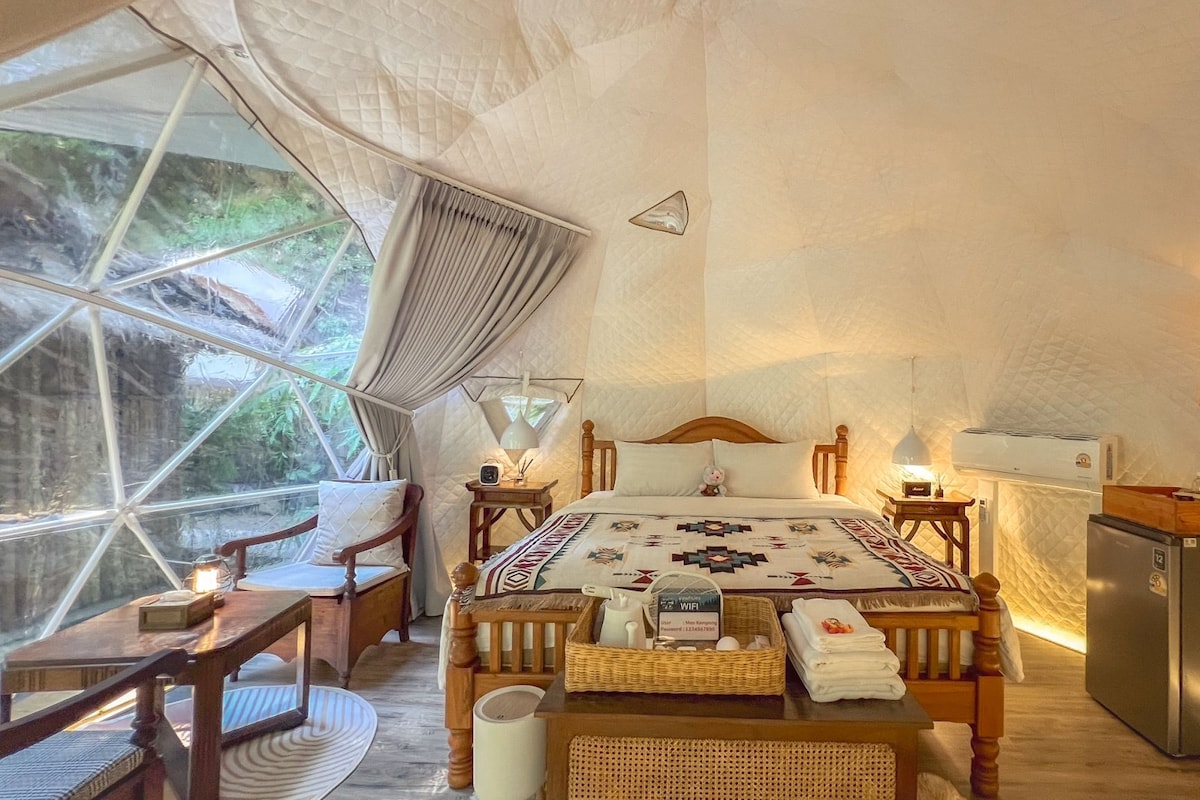 Um quarto aconchegante em estilo de tenda, com cama, mesas de cabeceira, escrivaninha e uma cadeira.