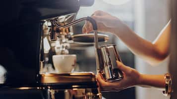Uma pessoa manuseando uma máquina de café, segurando uma xícara.