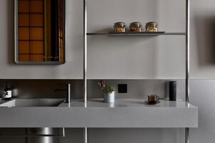 Uma cozinha moderna com uma pia embutida, uma prateleira com potes, uma planta em vaso e uma xícara.