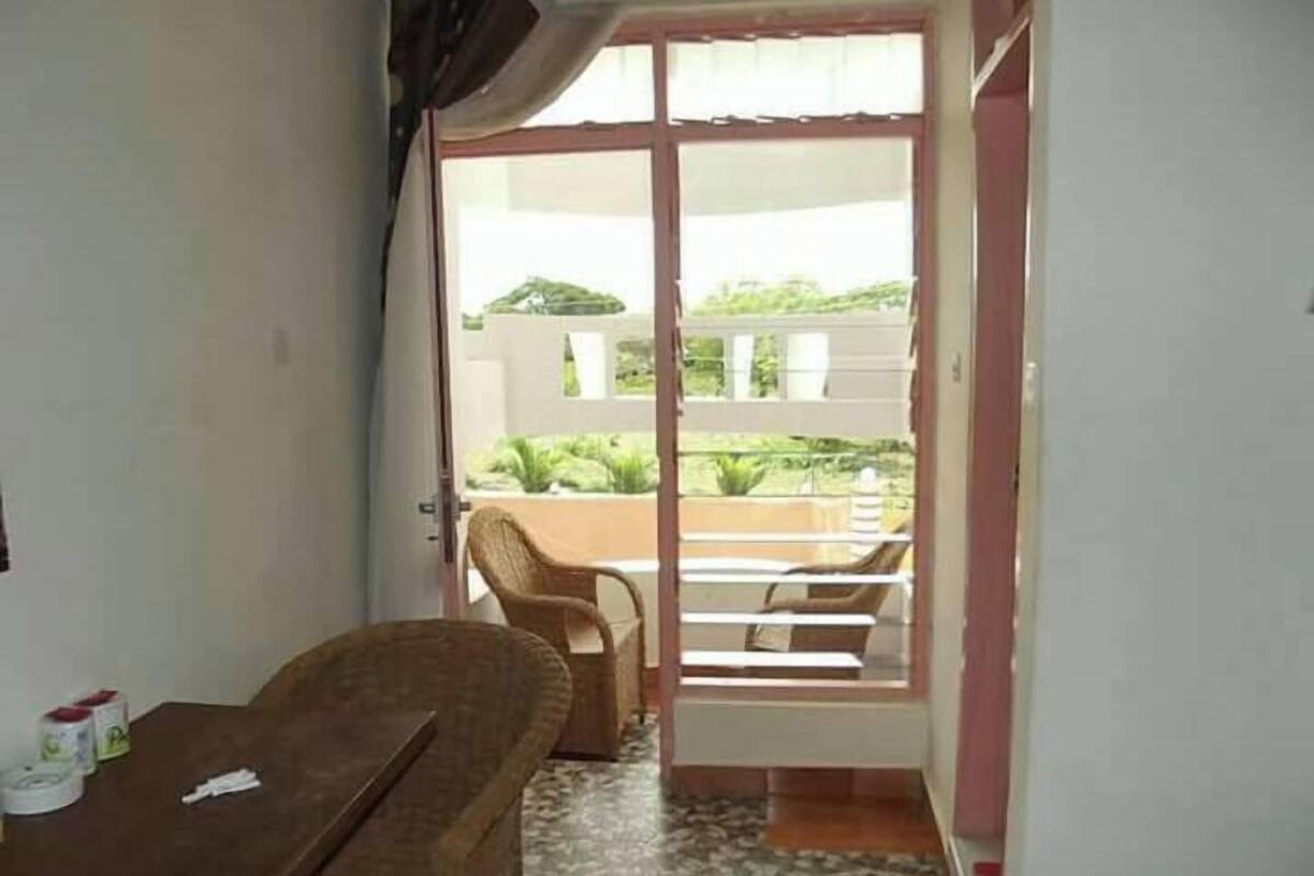 Quarto com porta de vidro deslizante que dá para área externa com mesa e cadeiras.