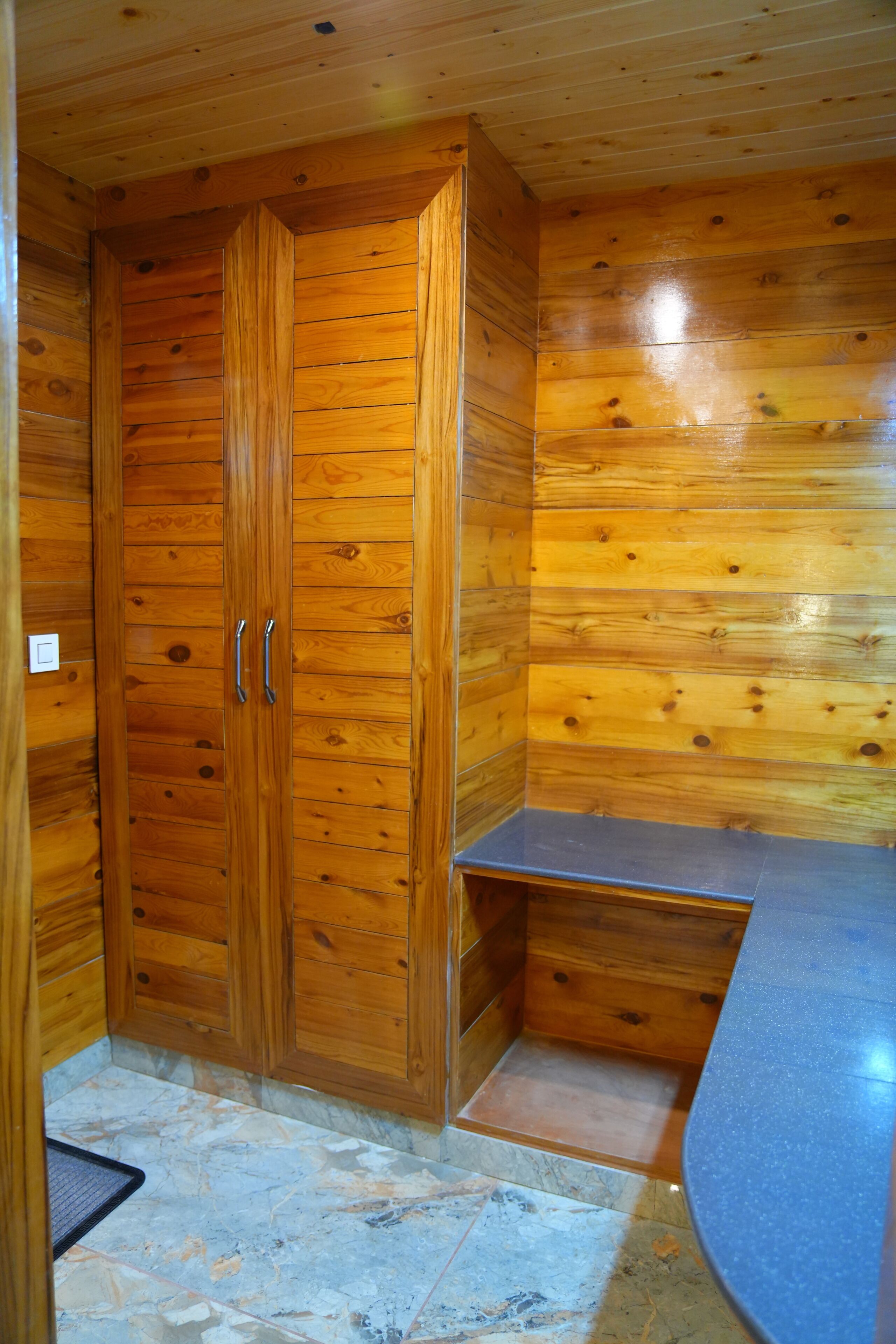 Um guarda-roupa de madeira com duas portas e um banco.