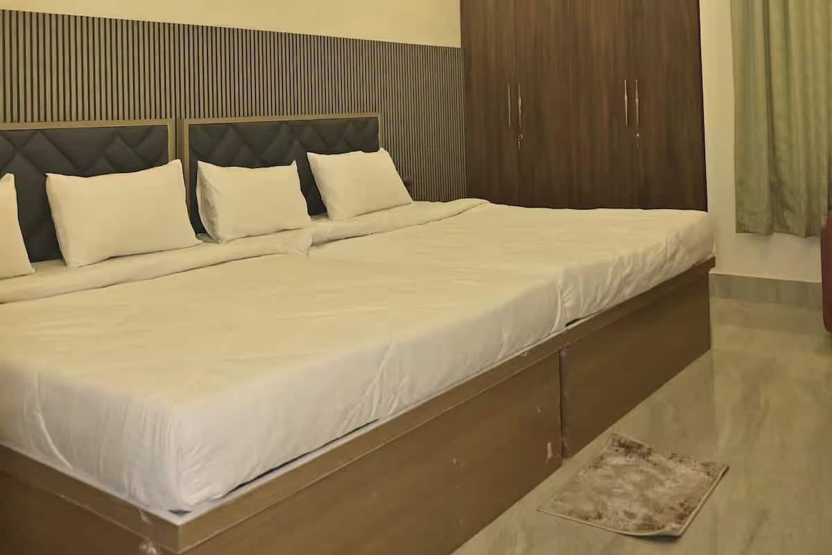 Uma cama com estrutura de madeira, cabeceira com ripas verticais e um tapete pequeno no chão.