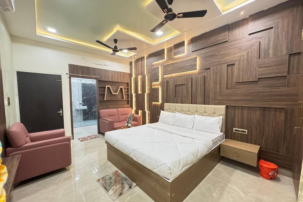 Quarto com uma cama grande, um ventilador de teto, um balde vermelho e um sofá rosa.