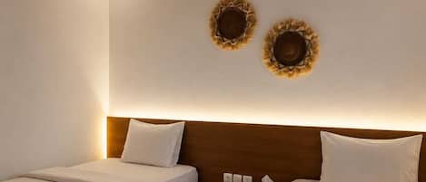 Quarto de hotel com duas camas, cabeceira de madeira e objetos decorativos fixados na parede.