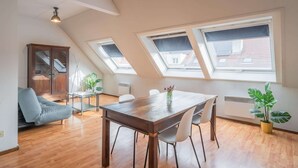 Um amplo loft com uma mesa de jantar de madeira, um sofá e claraboias.