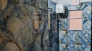 Casa de banho com paredes de mármore, chuveiro, lavatório e sanita.