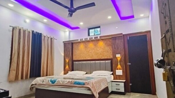 Quarto com cama, mesas de cabeceira, ventilador de teto e iluminação em roxo LED.