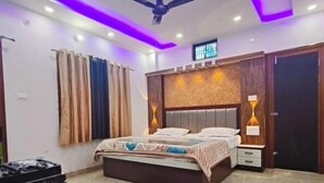 Quarto com cama, ventoinha no teto, mesa de cabeceira e escrivaninha com computador.