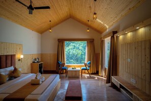 Quarto com cama, escrivaninha, duas cadeiras, janela com cortinas e ventilador de teto.