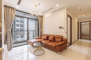 Uma sala de estar moderna com um sofá marrom, uma mesa de centro de vidro e uma janela grande com cortinas.