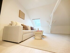 Uma sala de estar moderna com um sofá branco, uma mesinha lateral e um claraboia.